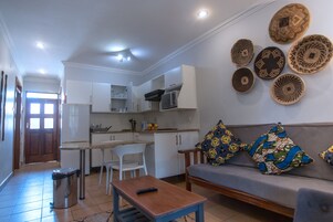 Um espaço compacto com cozinha compacta, área de jantar e sofá com almofadas estampadas.