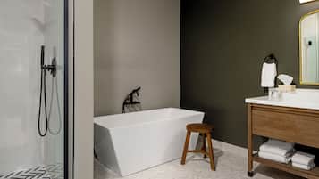 Uma casa de banho moderna com cabine de duche em vidro, uma banheira independente e uma toucador de madeira com espelho.