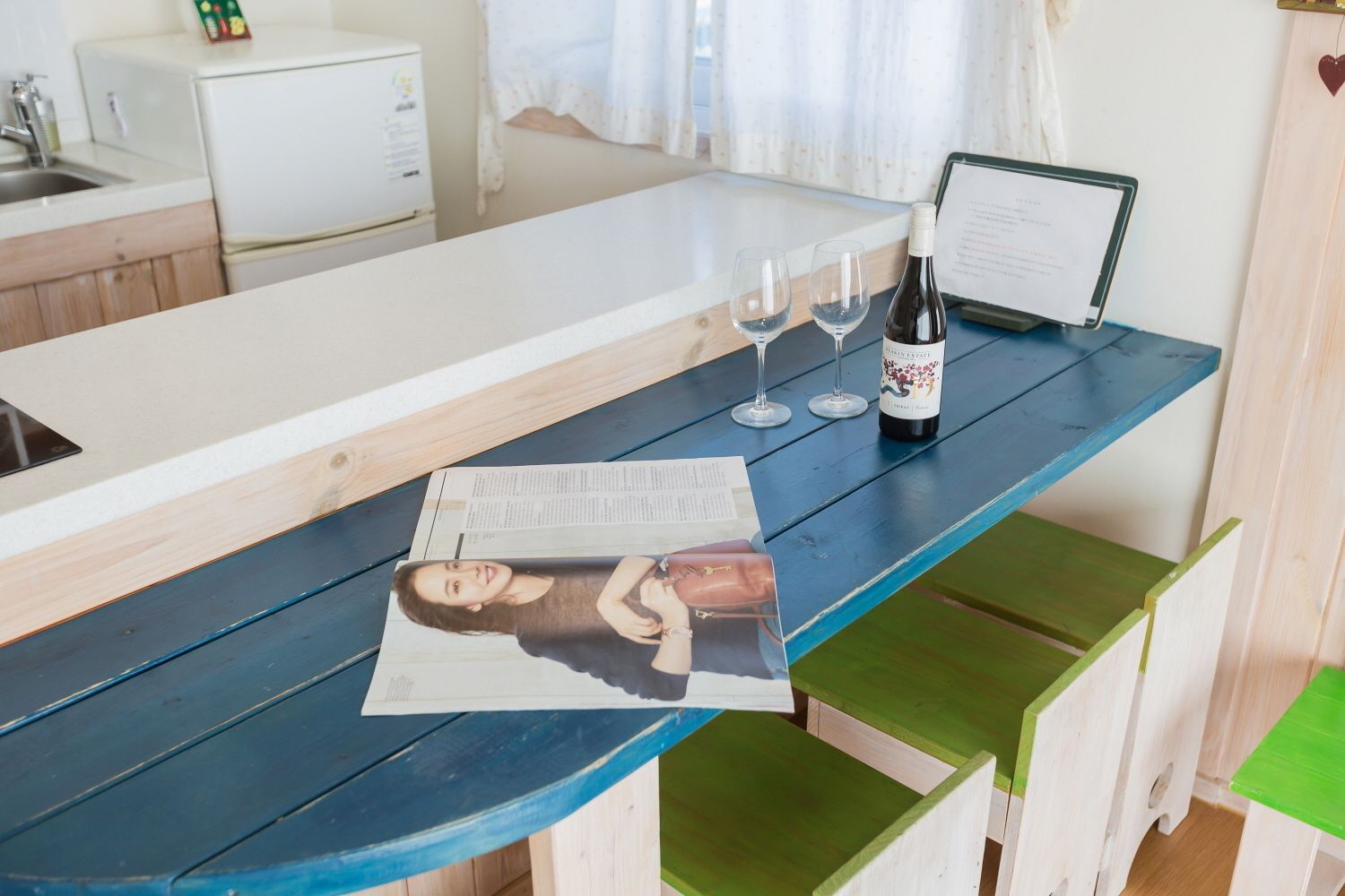Uma bancada de cozinha com uma garrafa de vinho, copos e um cardápio.