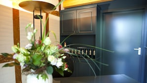 Um interior moderno com um vaso de flores brancas sobre uma superfície refletora, armários azul-escuros e teto de madeira.