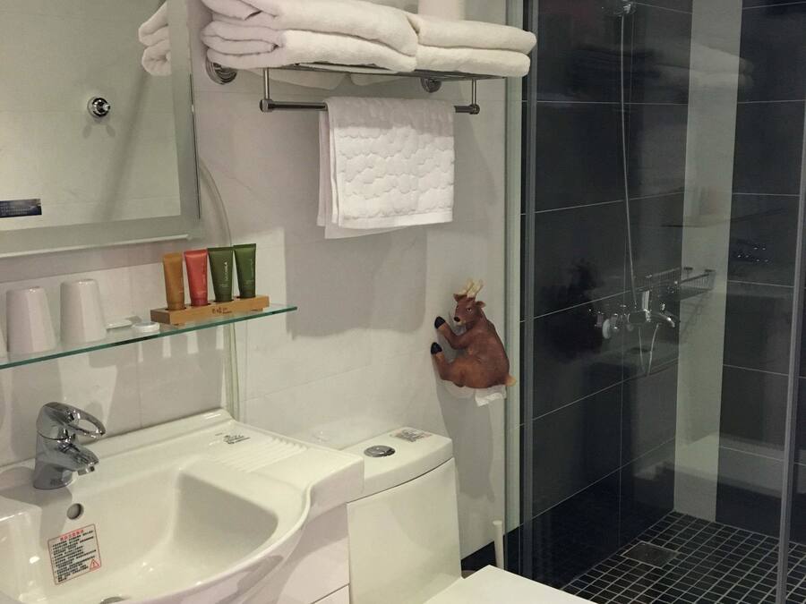 Casa de banho moderna com lavatório branco, sanita e cabine de duche em vidro.