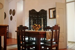 Uma área de refeições com uma mesa e cadeiras de madeira, um painel decorativo na parede e um espelho.