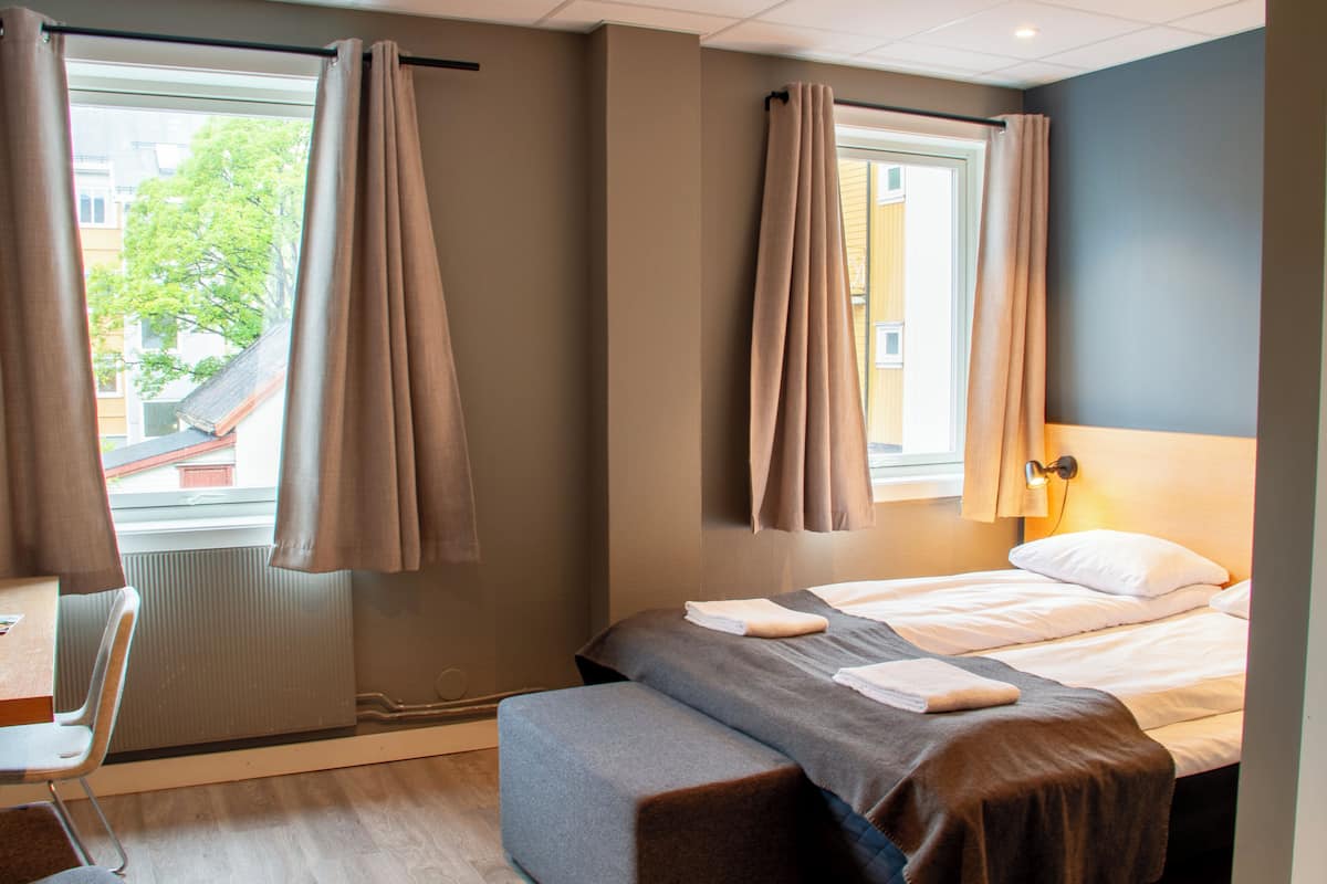 Quarto de hotel com duas camas, uma escrivaninha e vista para o exterior.