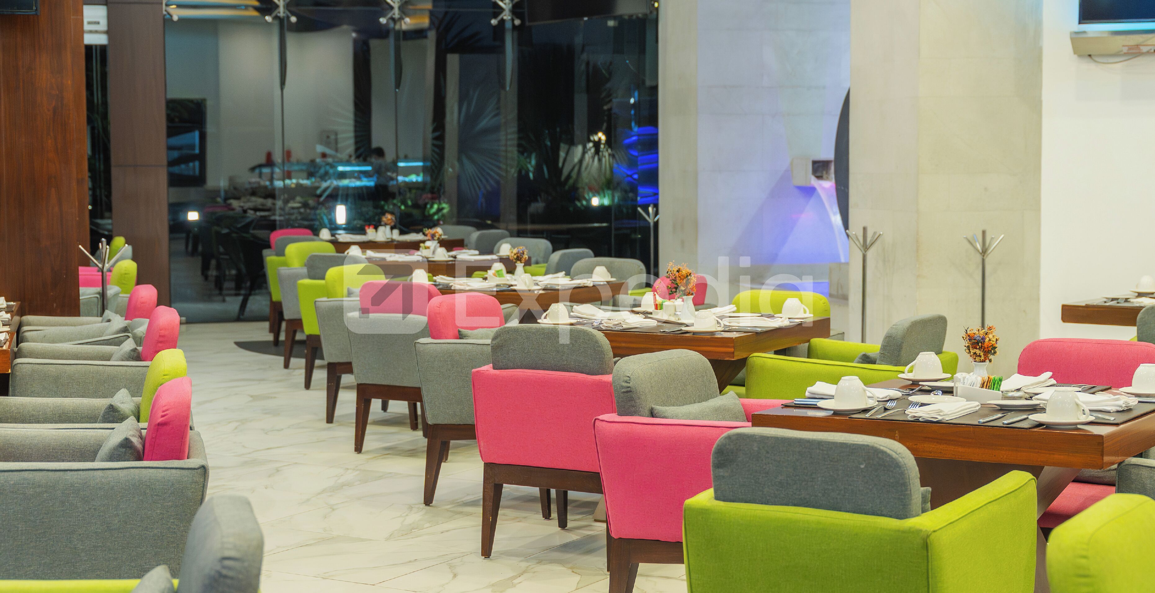 Um restaurante com várias mesas e cadeiras, algumas com almofadas coloridas.