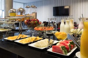 Buffet com diversas frutas, queijos e bebidas.