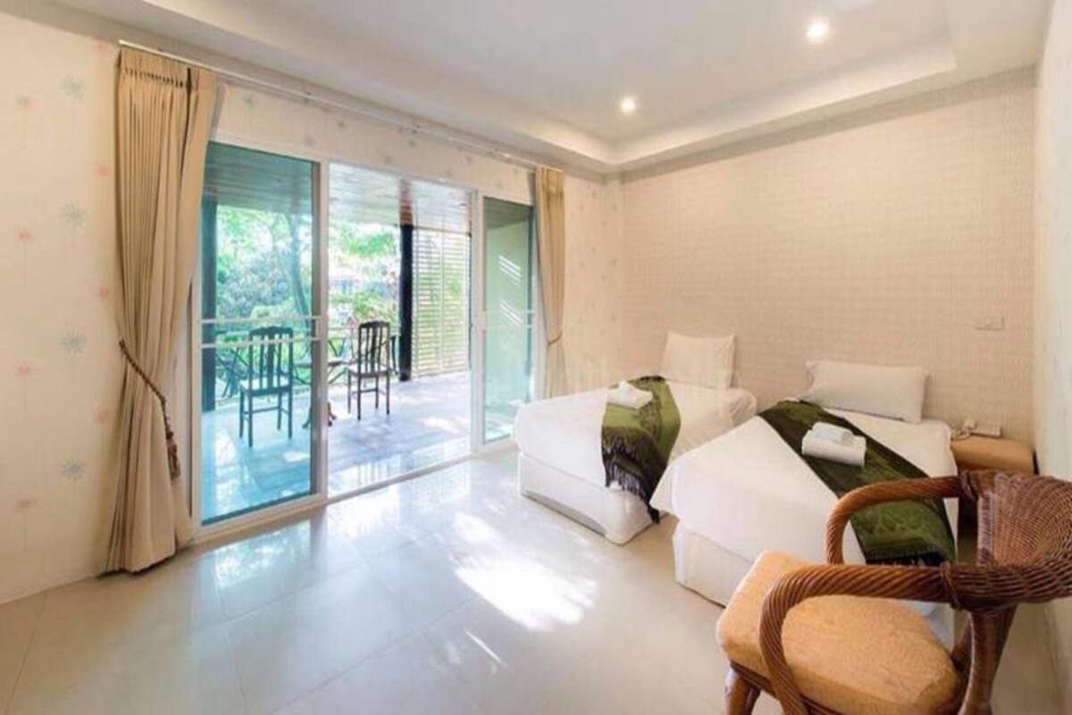 Quarto de hotel com uma cama, uma cadeira e vista para o exterior através de uma porta de correr.
