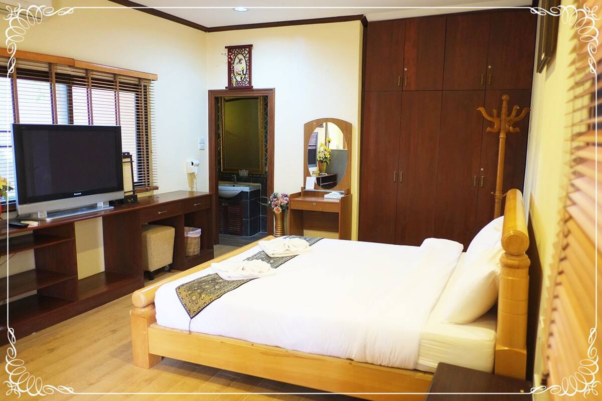 Quarto de hotel com uma cama, televisão, escrivaninha, espelho e guarda-roupa.