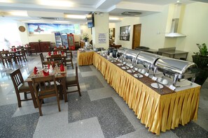 Organização de buffet com várias mesas, cadeiras e uma linha de buffet.