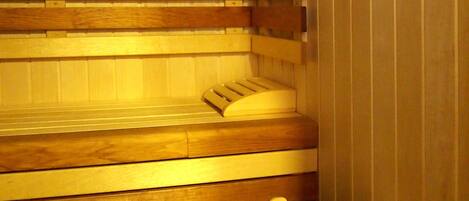 Um banco de sauna de madeira com assento e um pequeno balde de madeira com alça.