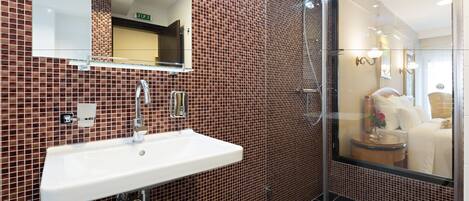 Um banheiro com pia branca, box de vidro e paredes com azulejos vermelhos.