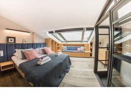 Um quarto moderno com claraboia, uma cama com almofadas, um espaço de estar e uma escrivaninha de madeira.