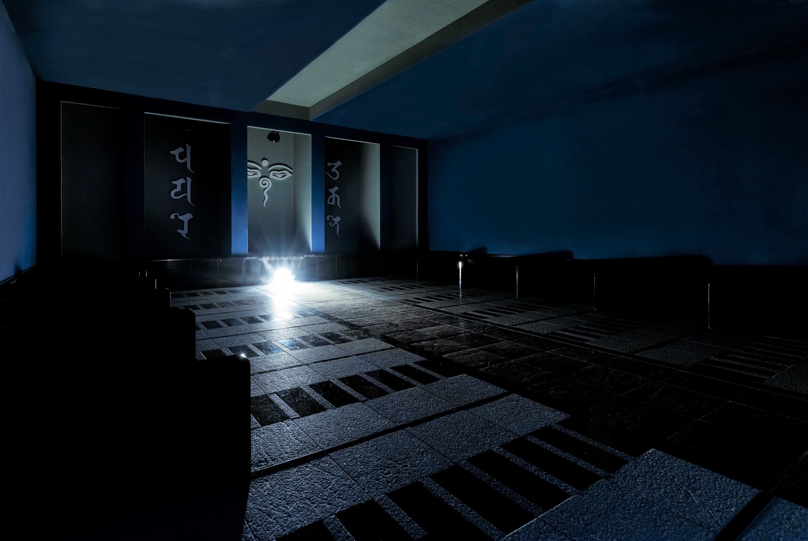 Um quarto com iluminação suave, chão de azulejos e uma fonte de luz no final do corredor.