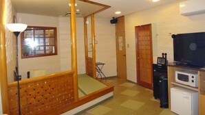 Quarto de hotel com cama de madeira, televisão, micro-ondas e frigorífico.