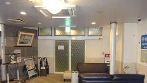 Um hall com balcão de recepção, área de espera com sofás de couro, máquina de café e máquina de venda automática.