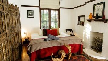 Quarto com cama, lareira, janela e painel decorativo na parede.