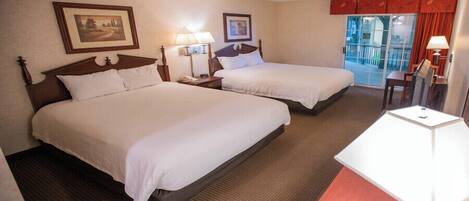Quarto de hotel com duas camas, uma escrivaninha e uma cadeira.
