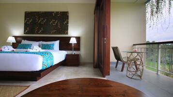 Quarto de hotel com cama, mesas de cabeceira, uma cadeira e varanda com vista.