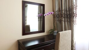 Quarto com cómoda de madeira escura, espelho, orquídea em vaso e cortina com padrão paisley.