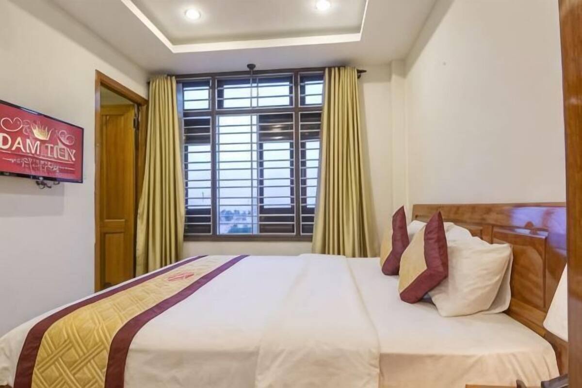 Quarto de hotel com cama, cortinas, janela e um aviso na parede.