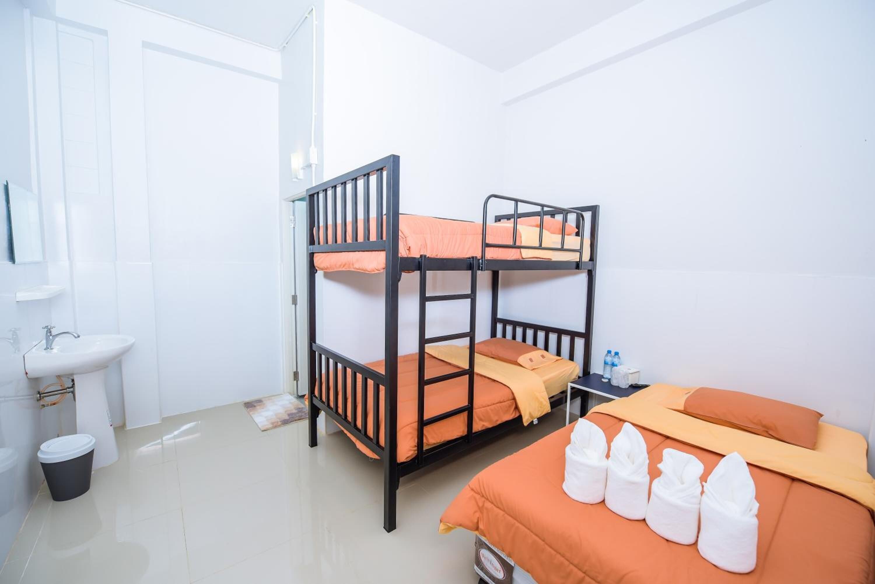Quarto com beliche, pia, lixeira e uma pequena mesa com artigos de higiene pessoal.
