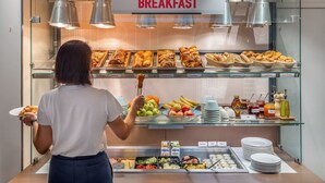 Buffet de café da manhã com diversos pães, frutas e acompanhamentos.