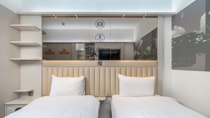 Quarto de hotel com duas camas, televisão integrada, espelho e uma obra de arte com paisagem urbana.