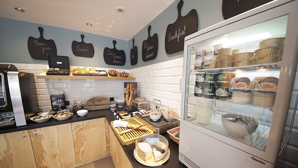 Um buffet de café da manhã com diversos alimentos e uma geladeira repleta de produtos lácteos.