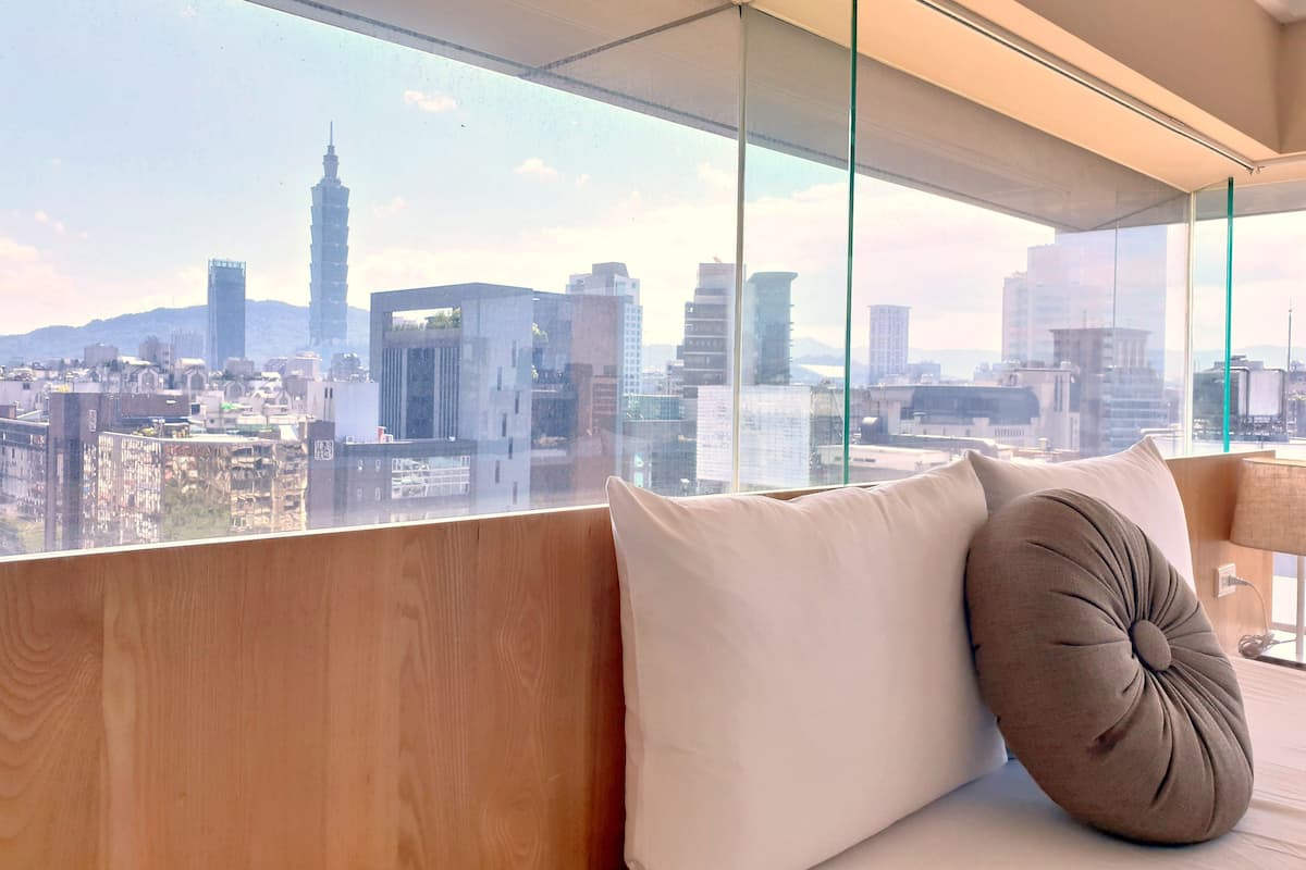 Quarto moderno com uma grande janela que oferece vista para a paisagem urbana, incluindo uma torre imponente.