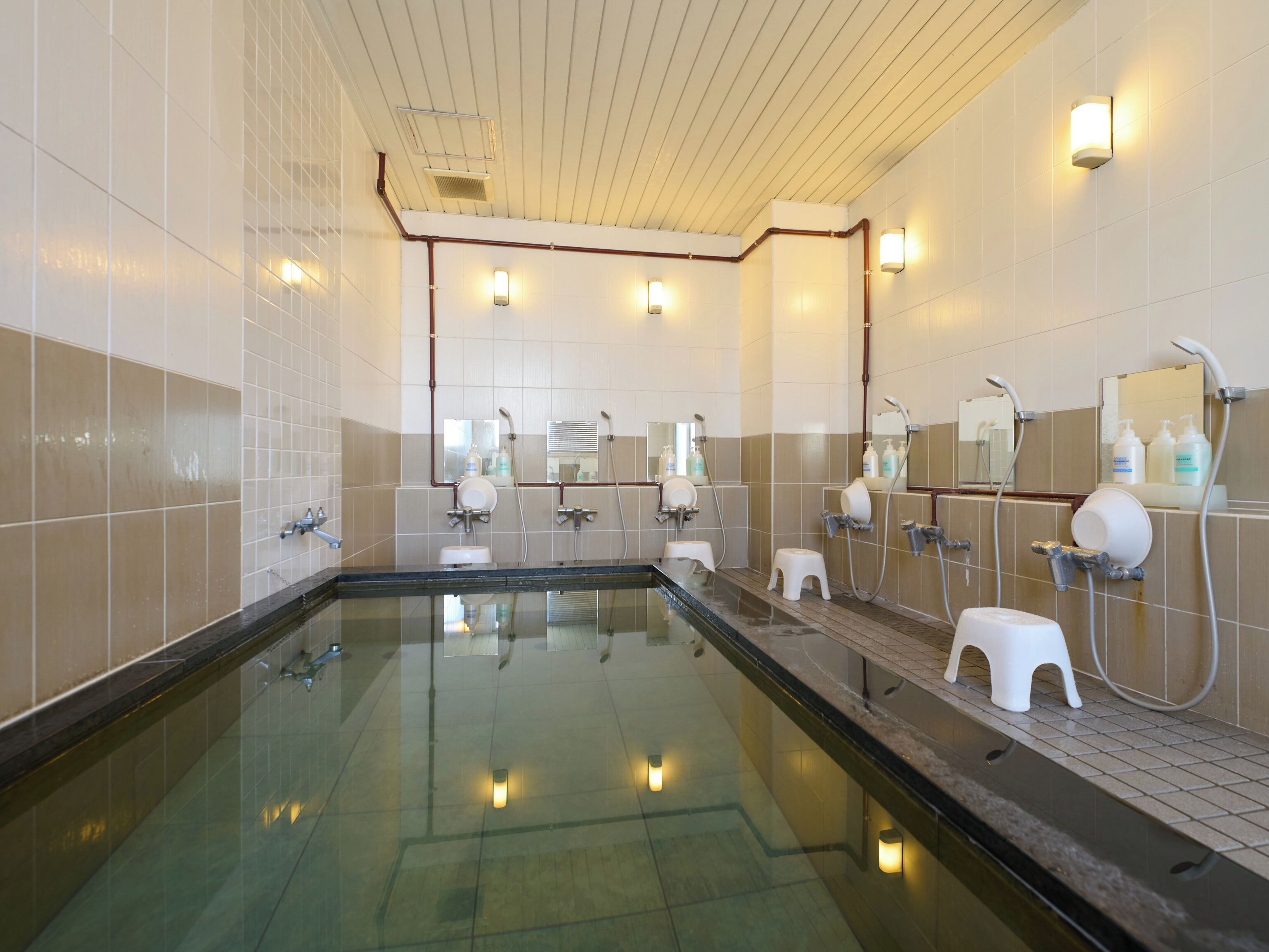 Um banheiro moderno com um espelho grande, várias pias e uma área de piscina central.