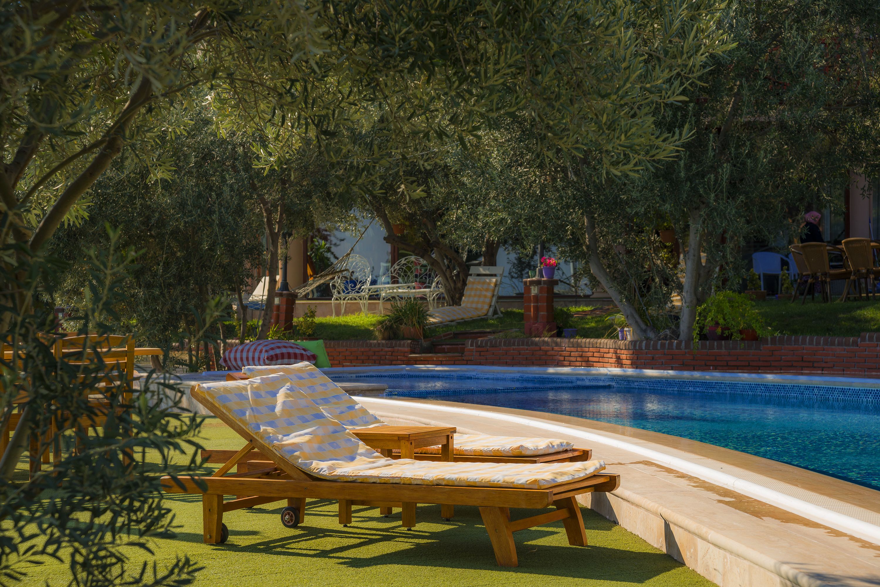 Área de piscina com espreguiçadeiras e uma parede de tijolos.