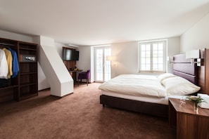 Quarto com cama, escrivaninha, televisão e guarda-roupa.