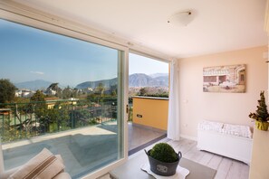 Uma varanda com vista ampla da paisagem ao redor, um banco branco e um vaso com planta.