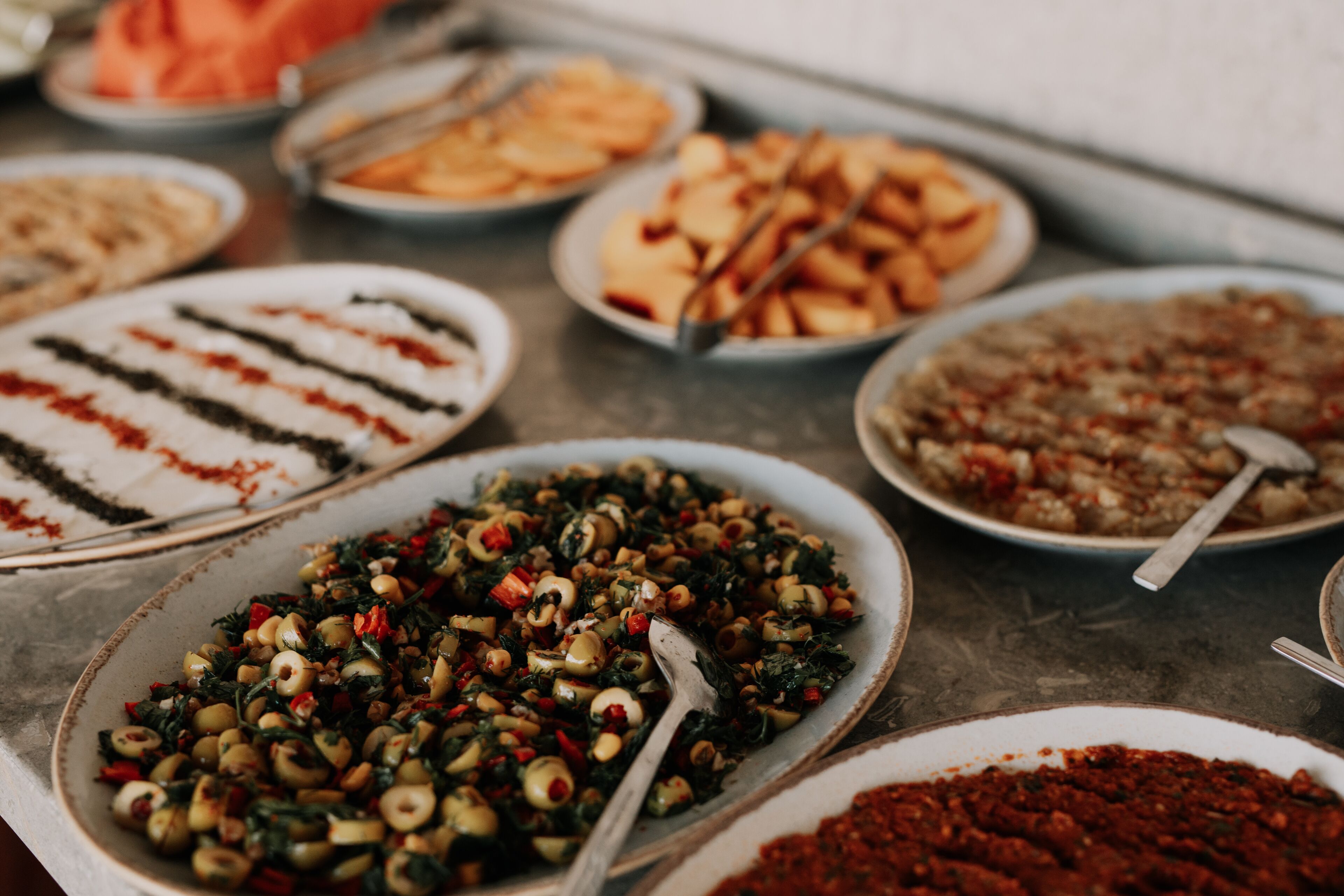 Buffet com diversos pratos, incluindo salada, massas e outros alimentos já preparados.