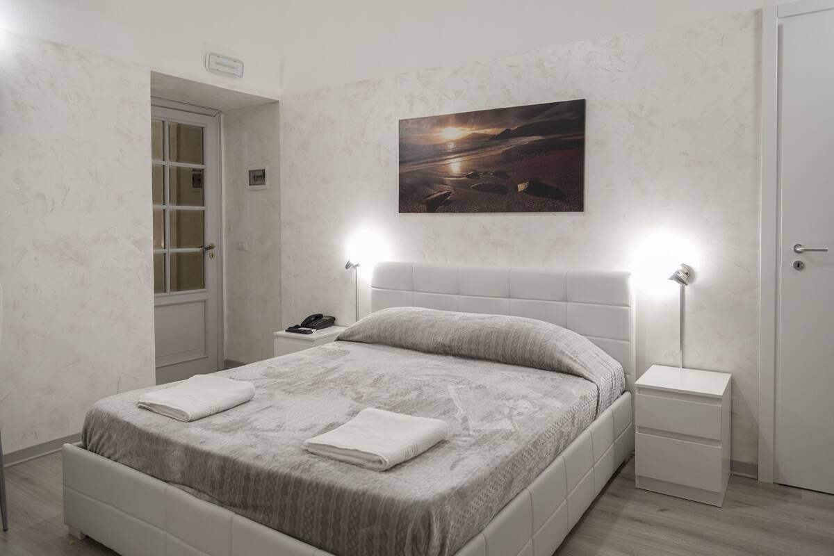 Quarto bem organizado com cama, mesas de cabeceira e uma porta.
