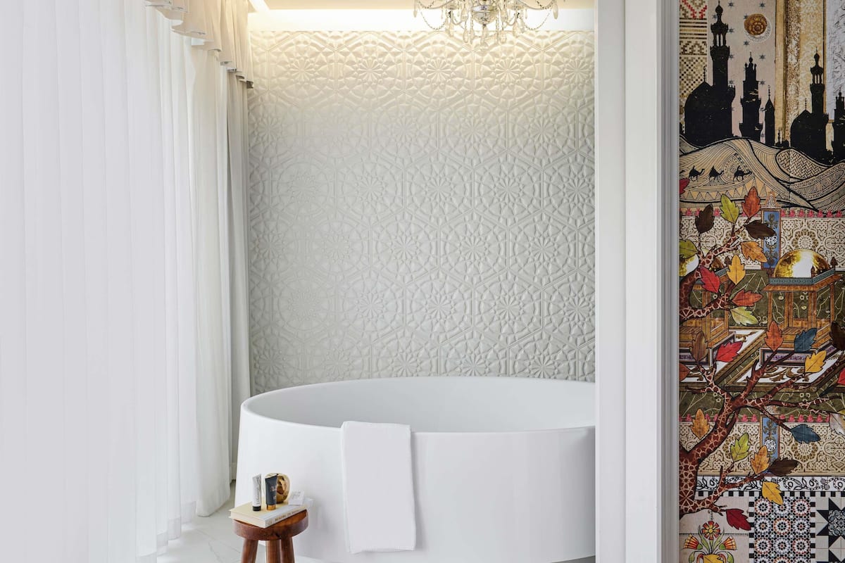 Um banheiro moderno com uma banheira grande, um candelabro e uma parede decorativa com padrão geométrico.