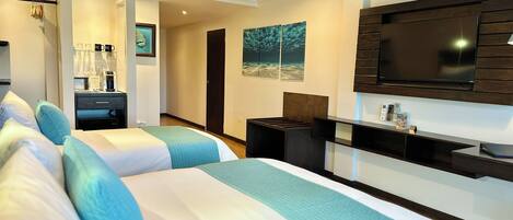Quarto de hotel moderno com uma cama grande, TV fixada na parede, escrivaninha com cadeira e ventoinha no teto.