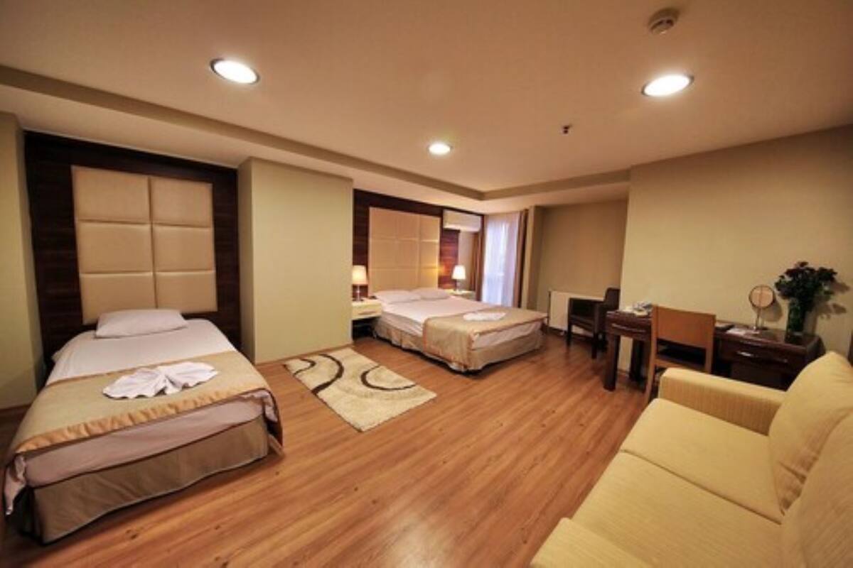 Quarto de hotel com duas camas, um sofá, uma mesa e uma cadeira.