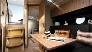 Um interior compacto e moderno, com mesa de madeira, assentos acolchoados e um claraboia.