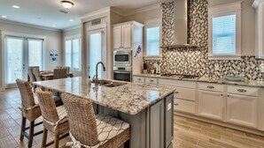 Uma cozinha ampla com uma ilha grande, eletrodomésticos embutidos e um painel de backsplash estampado.
