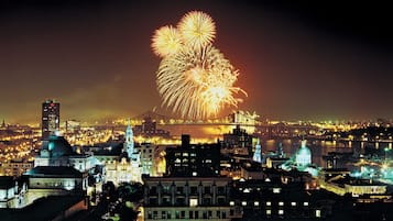 Paisagem urbana noturna com fogos de artifício, edifícios e uma ponte.