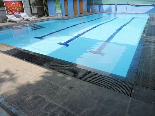 Piscina com divisórias de pista bem definidas, um deck revestido de azulejos e uma placa de sinalização ao fundo.