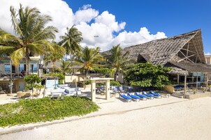 Na praia, areia branca, espreguiçadeiras, guarda-sóis 