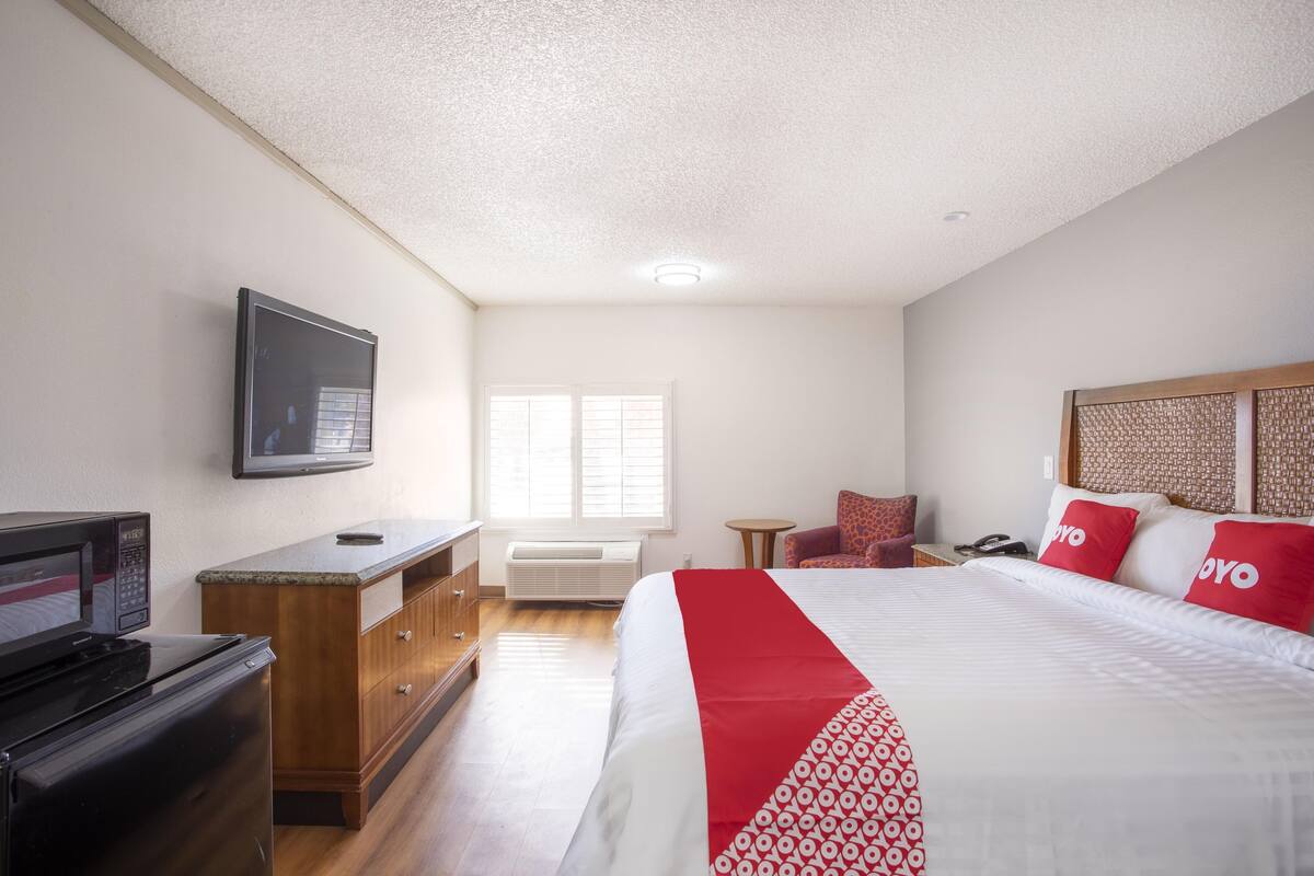 Quarto de hotel com cama, televisão, escrivaninha e cadeira.