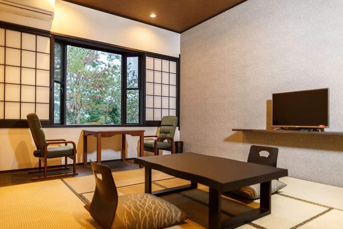 Um quarto em estilo japonês tradicional, com tatames, uma mesa baixa e cadeiras.