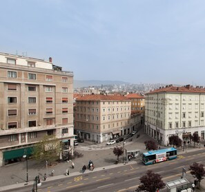 Ruas da cidade com edifícios, um ônibus e pedestres.