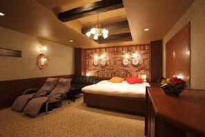 Quarto de hotel com cama, cadeiras de massagem, parede de tijolos e lustre.