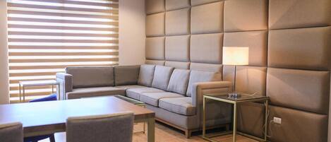 Uma sala de estar moderna com um sofá modular, uma mesa de centro de vidro e um abajur.