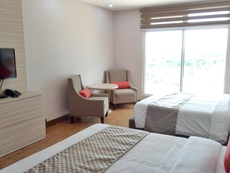 Quarto de hotel com cama, televisão, escrivaninha e cadeira.