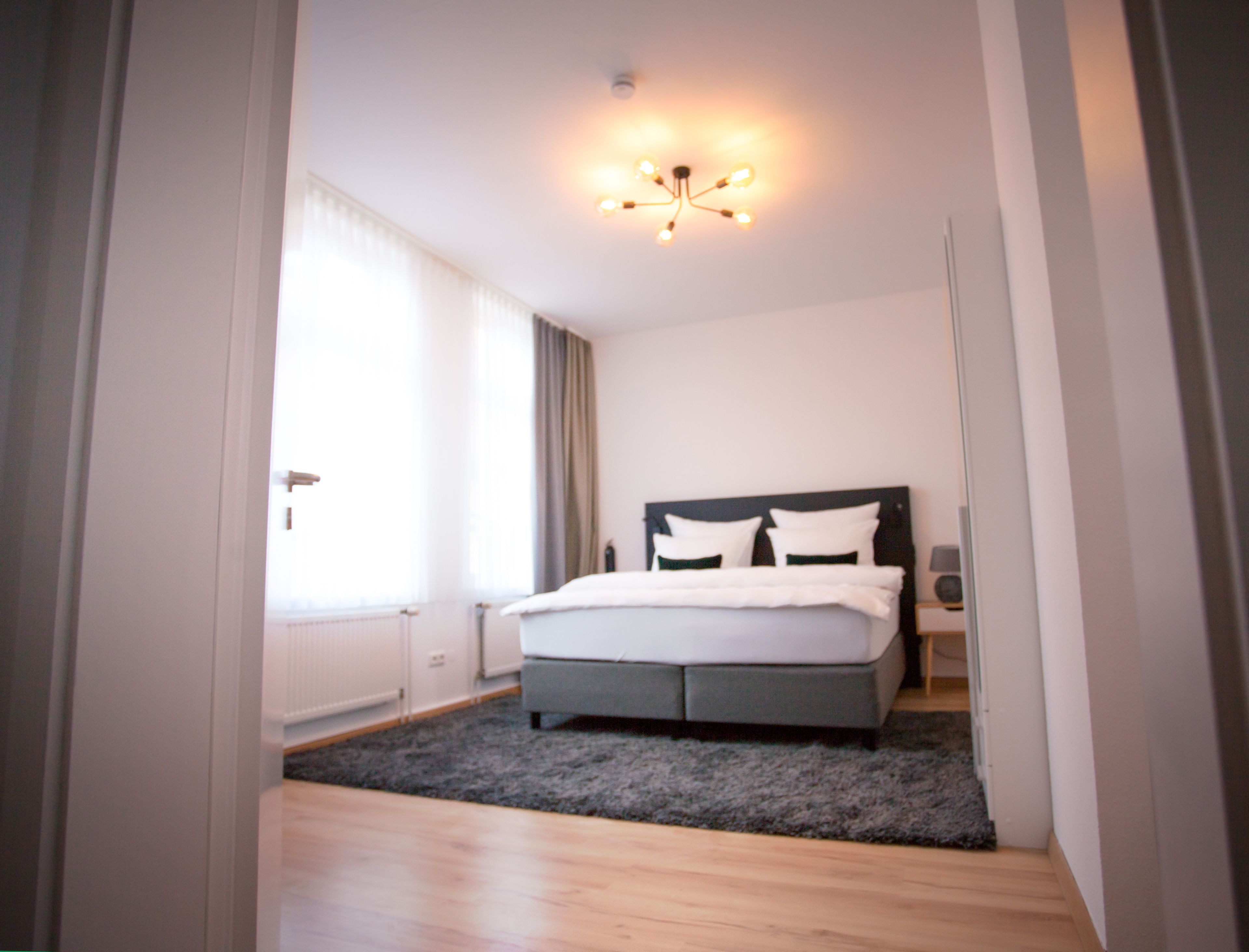 Quarto moderno com cama grande, mesa de cabeceira, luminária e luminária de teto.