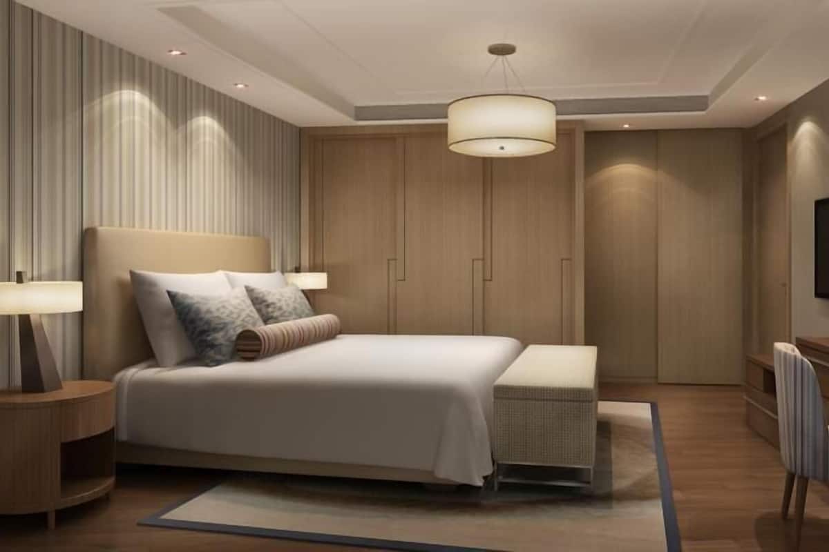 Quarto moderno com uma cama grande, luminárias de cabeceira, uma TV e uma escrivaninha de madeira.